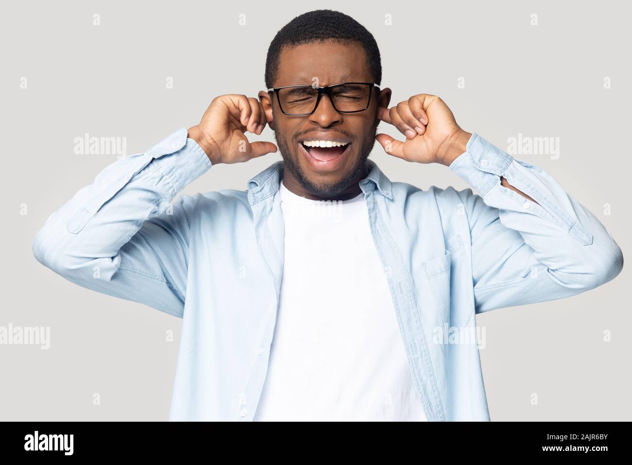 African guy shouting plugging his ears feels annoyed studio shot Stock ...