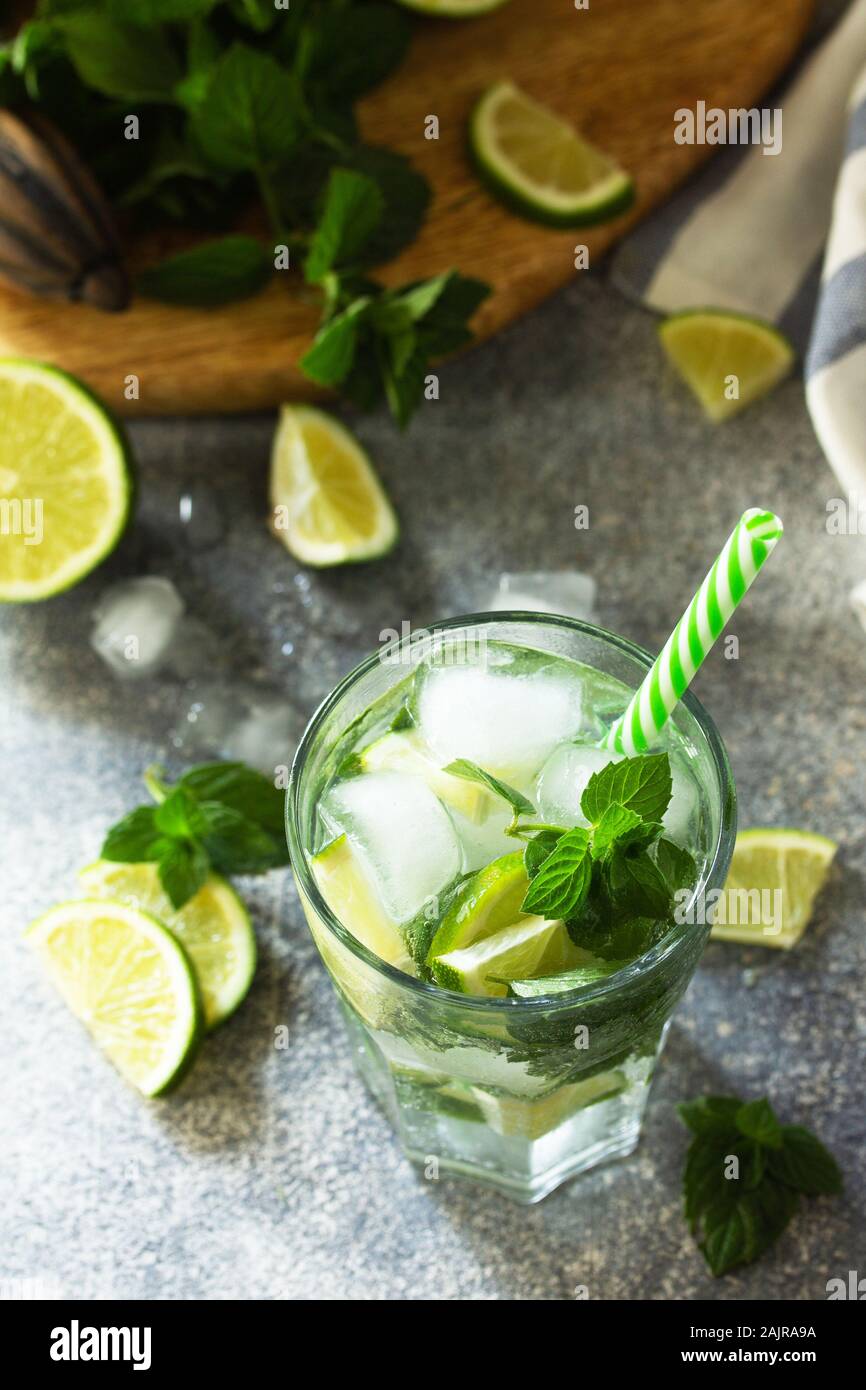 Fresh Mojito cocktail with lime, ice and mint in a glass on a gray ...