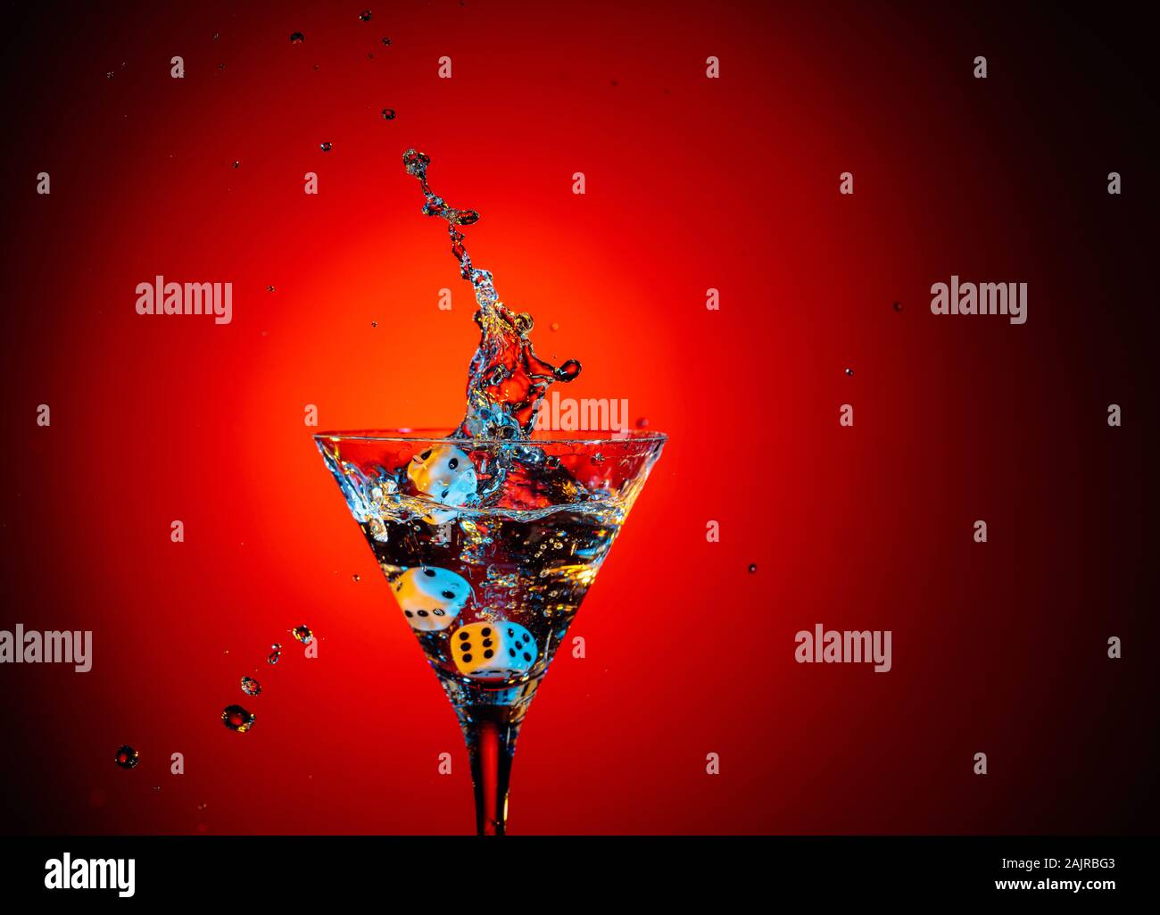 Dice fall in a glass of martini. Colourful cocktail in glass with ...