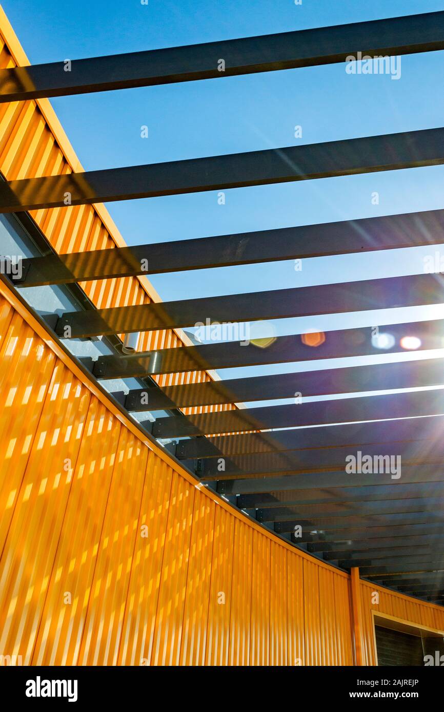 abstract bright yellow corrugated metal and roof beams against blue sky ...