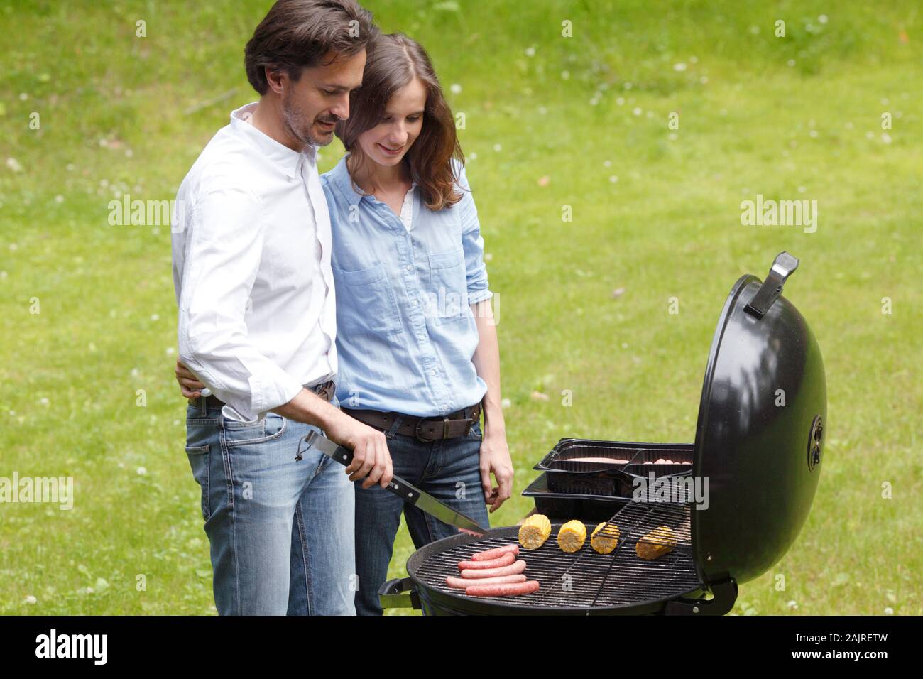 Happy couple cooking food on barbecue Stock Photo - Alamy