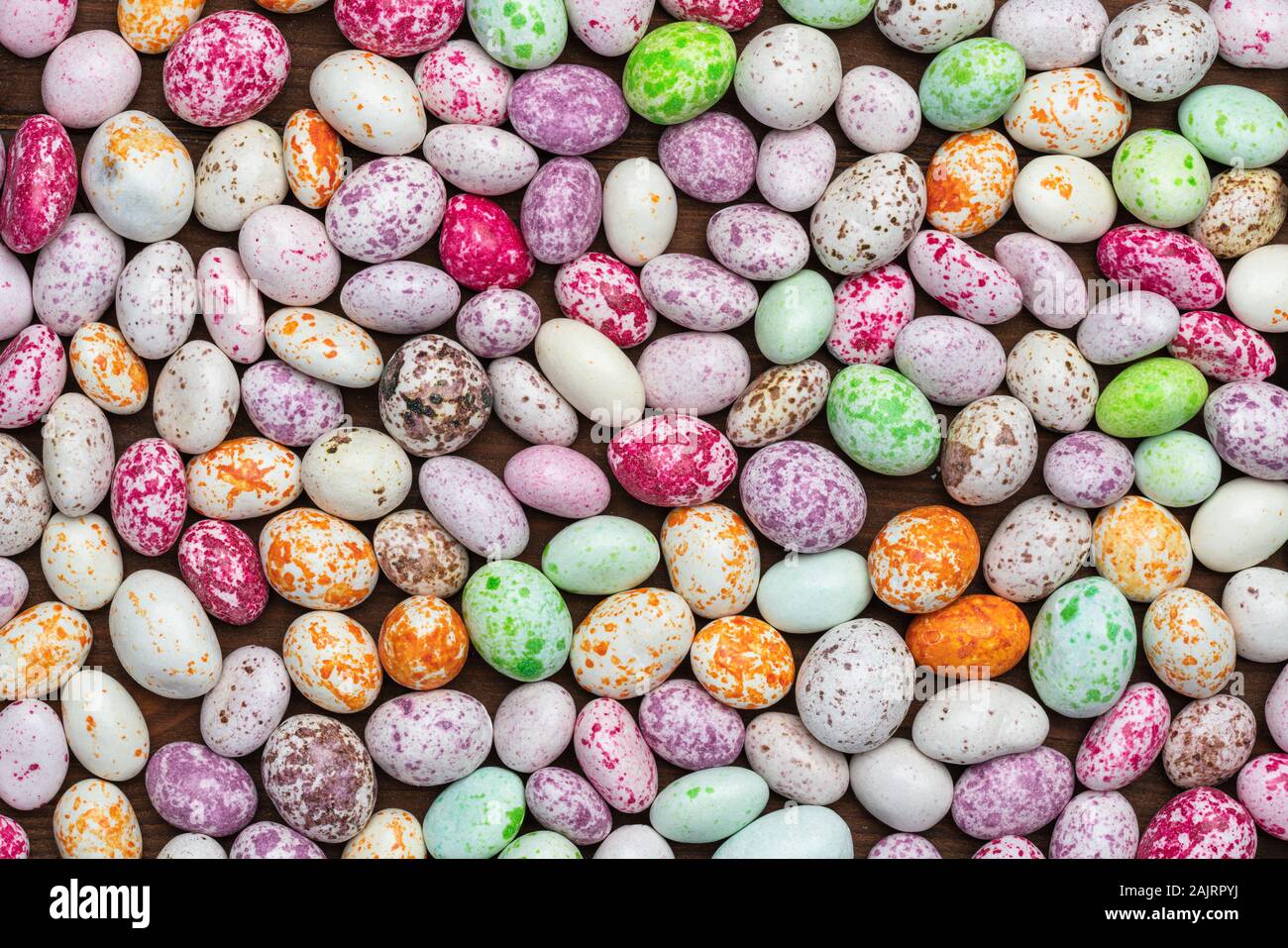 Mix of sweets in the form of multi-colored spotted pebbles on a brown ...