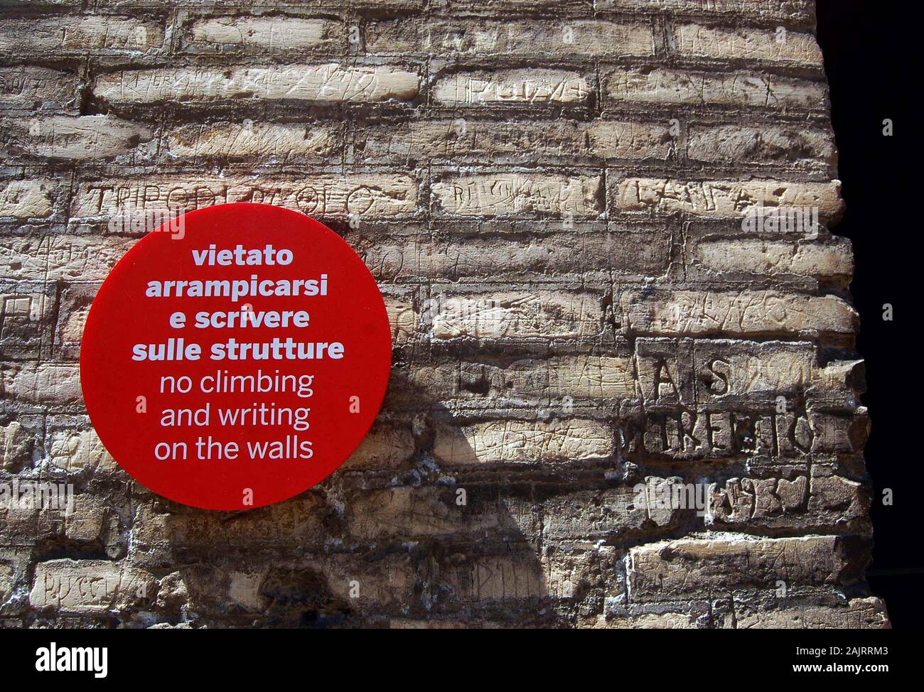 A sign surrounded by historic graffiti on stone wall in the famous ...