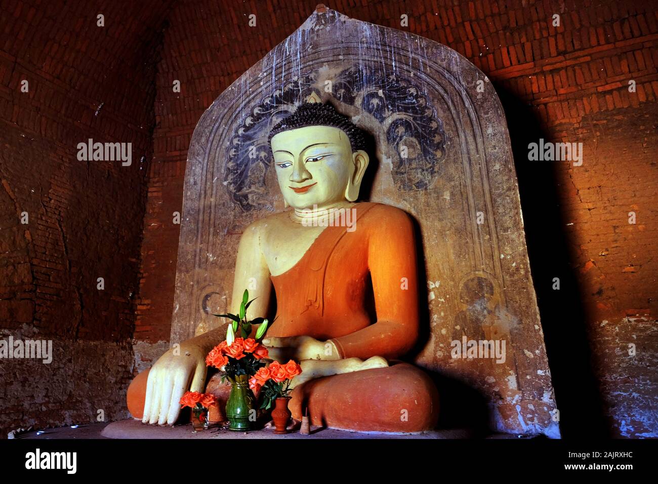 Ancient Buddha statue in a temple in old Bagan, Myanmar, covered in red ...