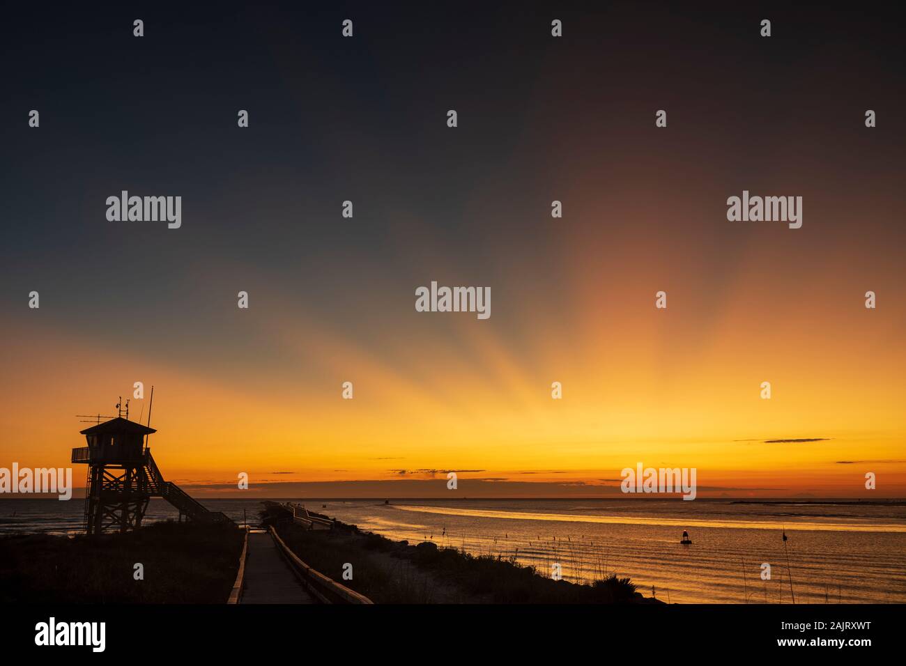 Sunbeams shine over the horizon at sunrise forming the shape of a crown ...