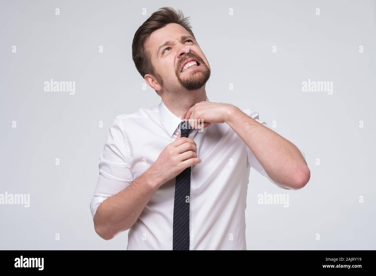 Angry young businessman pulling his tie feeling ill. I need a fresh air ...