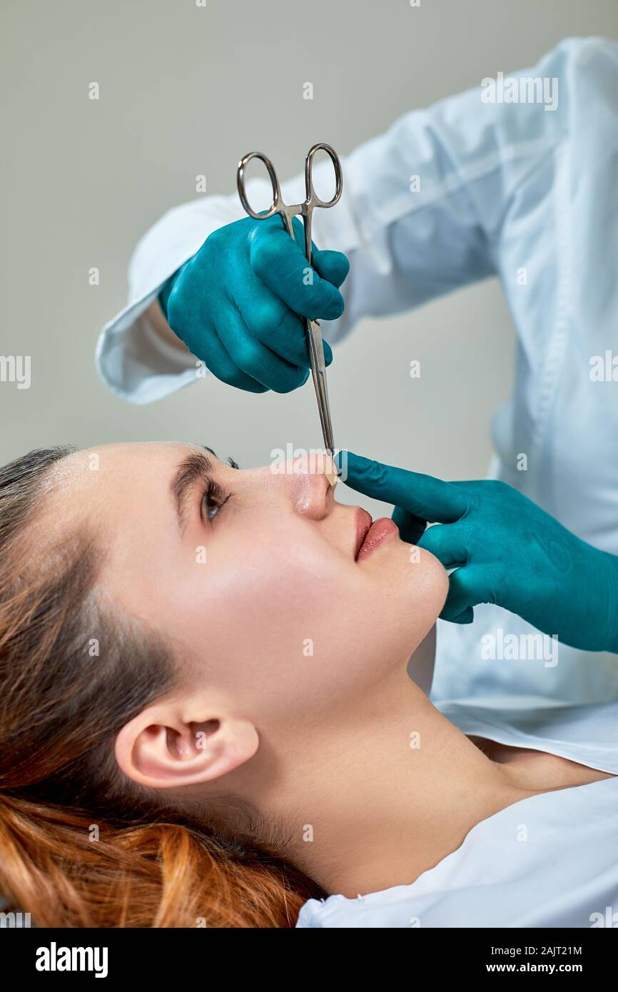 Lady with plaster on nose, doctor examining patients face after plastic ...