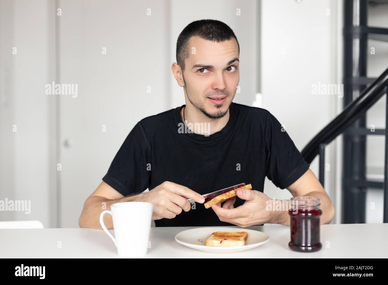 The guy has breakfast with toast with jam Stock Photo - Alamy
