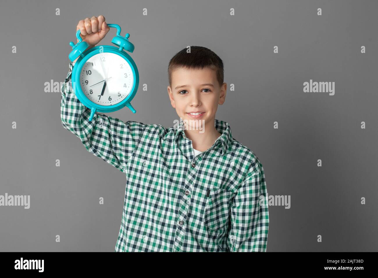 Freestyle. Boy standing isolated on grey wall with alarm clock up ...