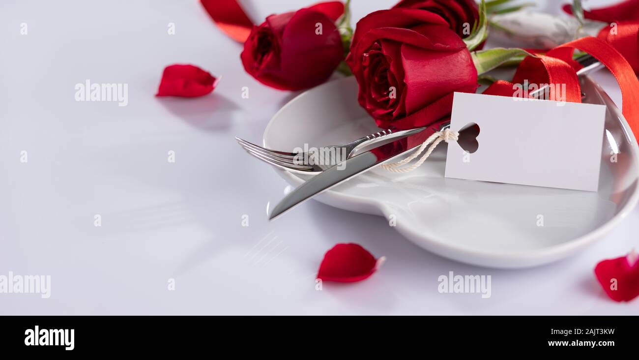 Table setting with a white paper card. White plates, cutlery and ...