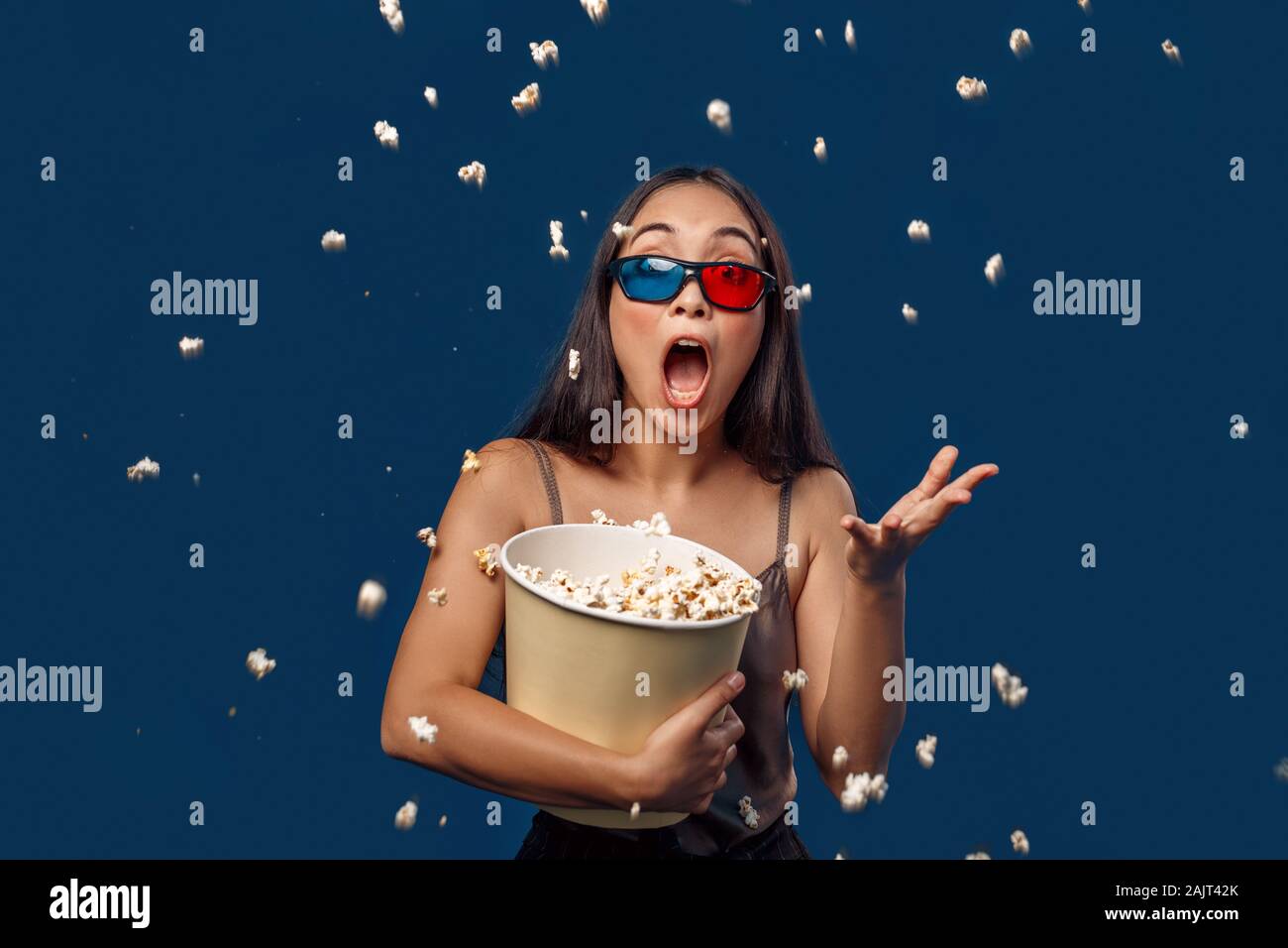 Freestyle. Young woman in 3d glasses standing isolated on dark blue ...