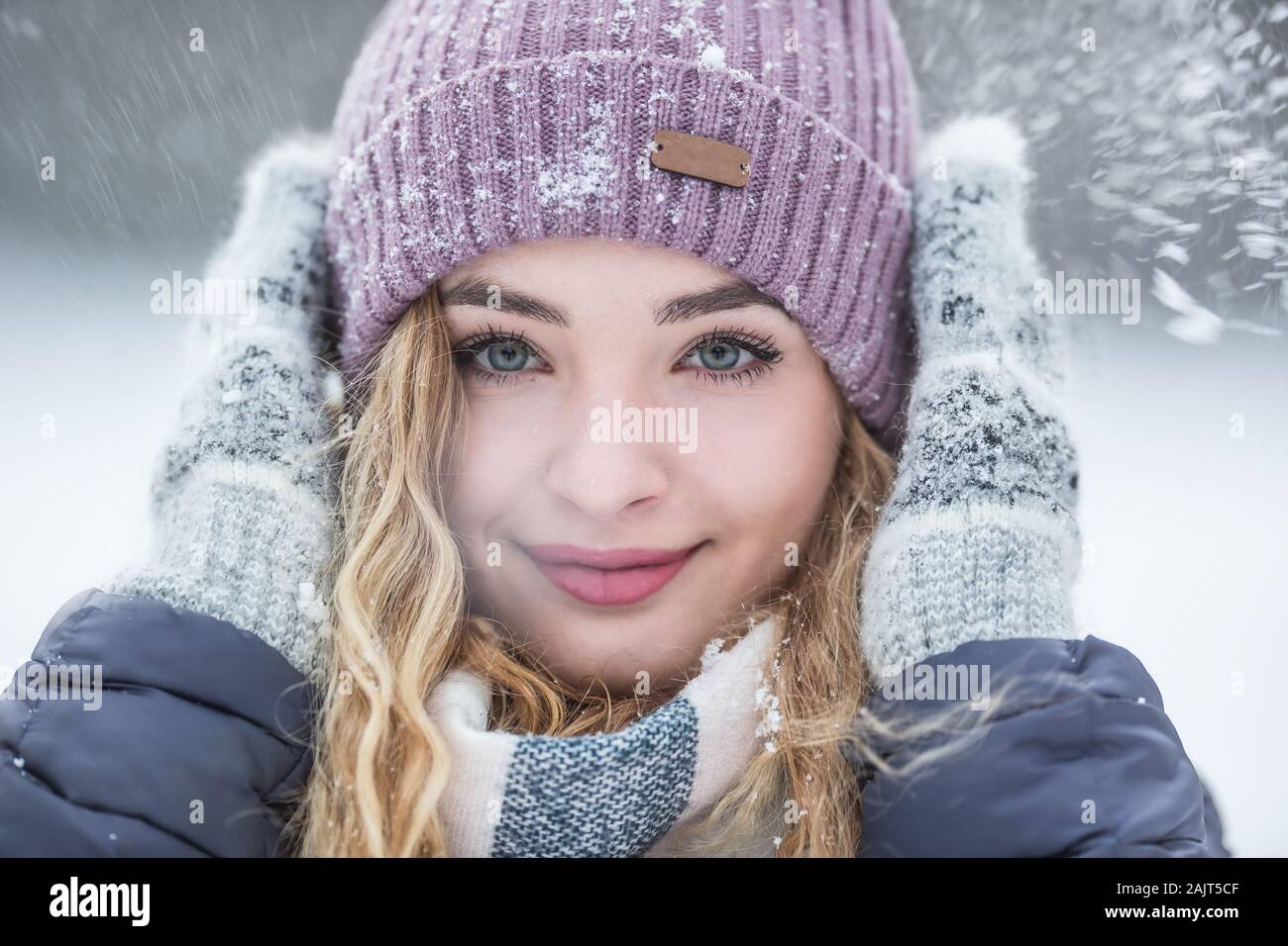 Portrait of young beautiful woman in winter clothes and strong snowing ...