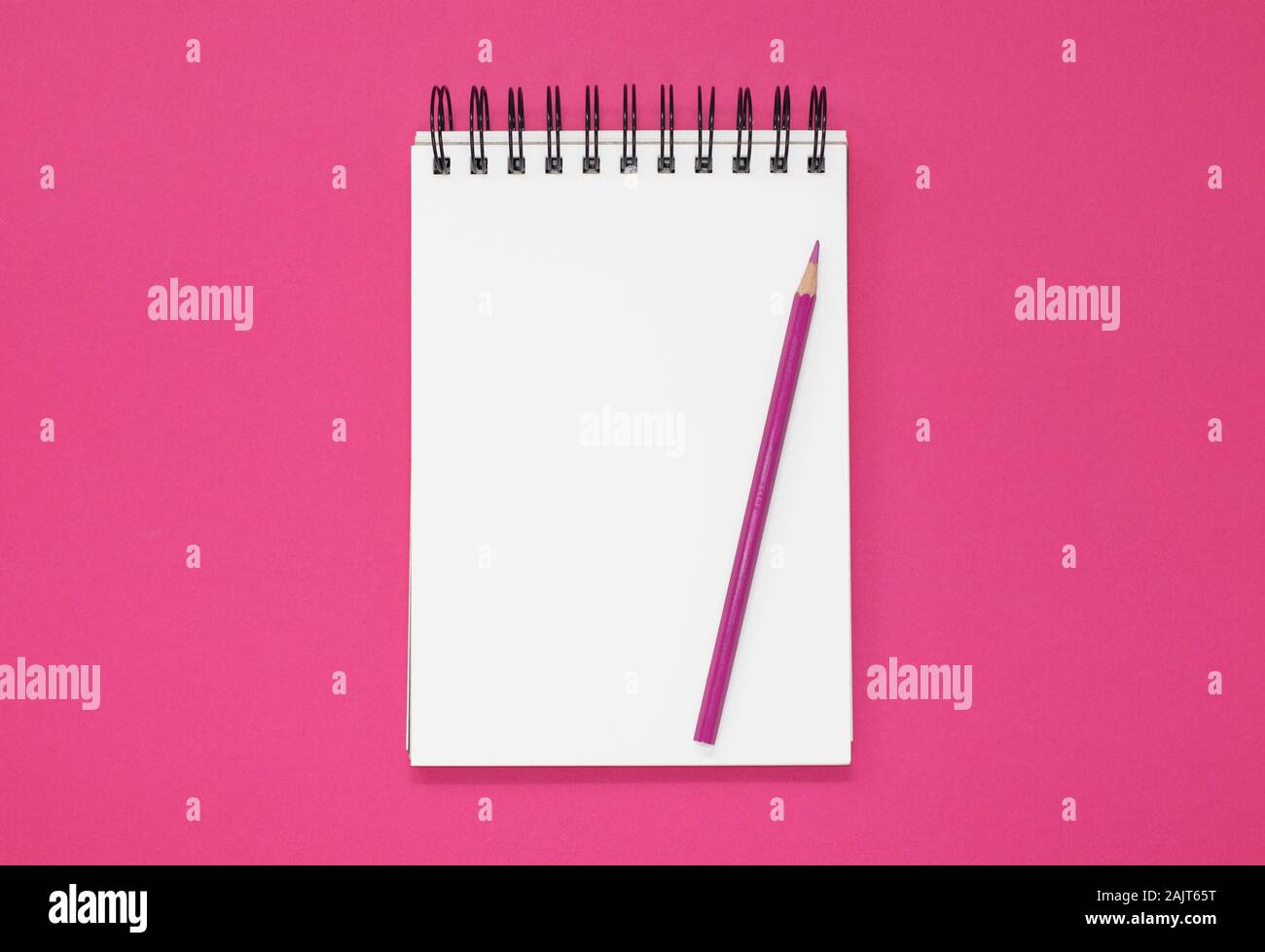 Open notepad and pencil on a hot pink background. Top view with copy ...