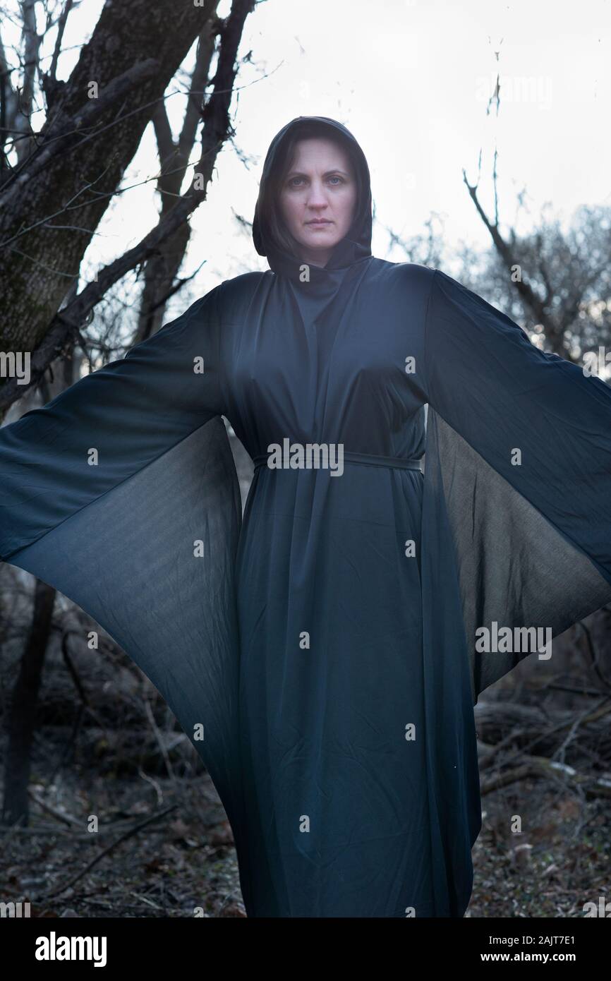Hooded Woman in black robes deep in the Forest. Witches. Halloween and ...