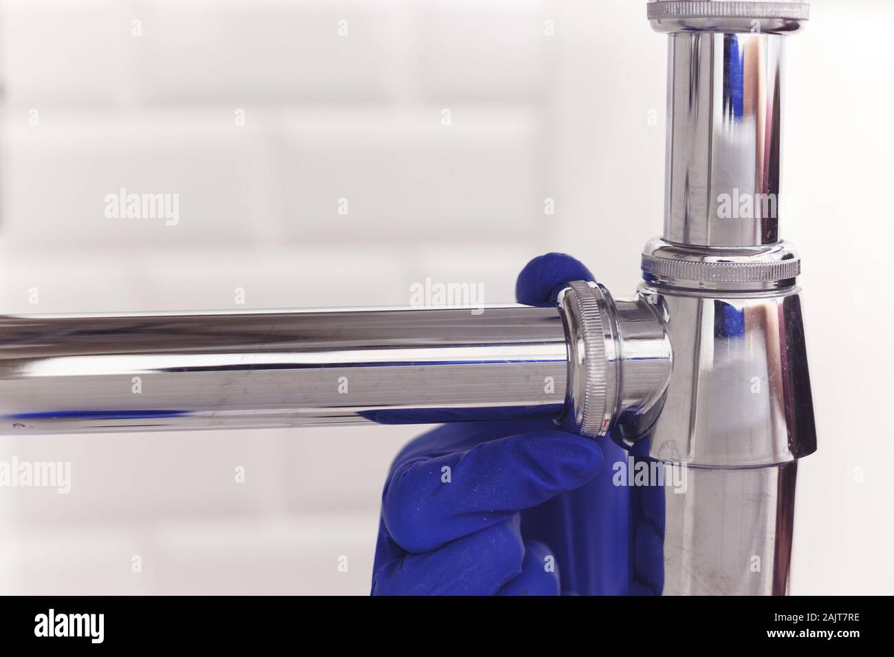 Plumber repairs and maintains chrome siphon under the washbasin ...