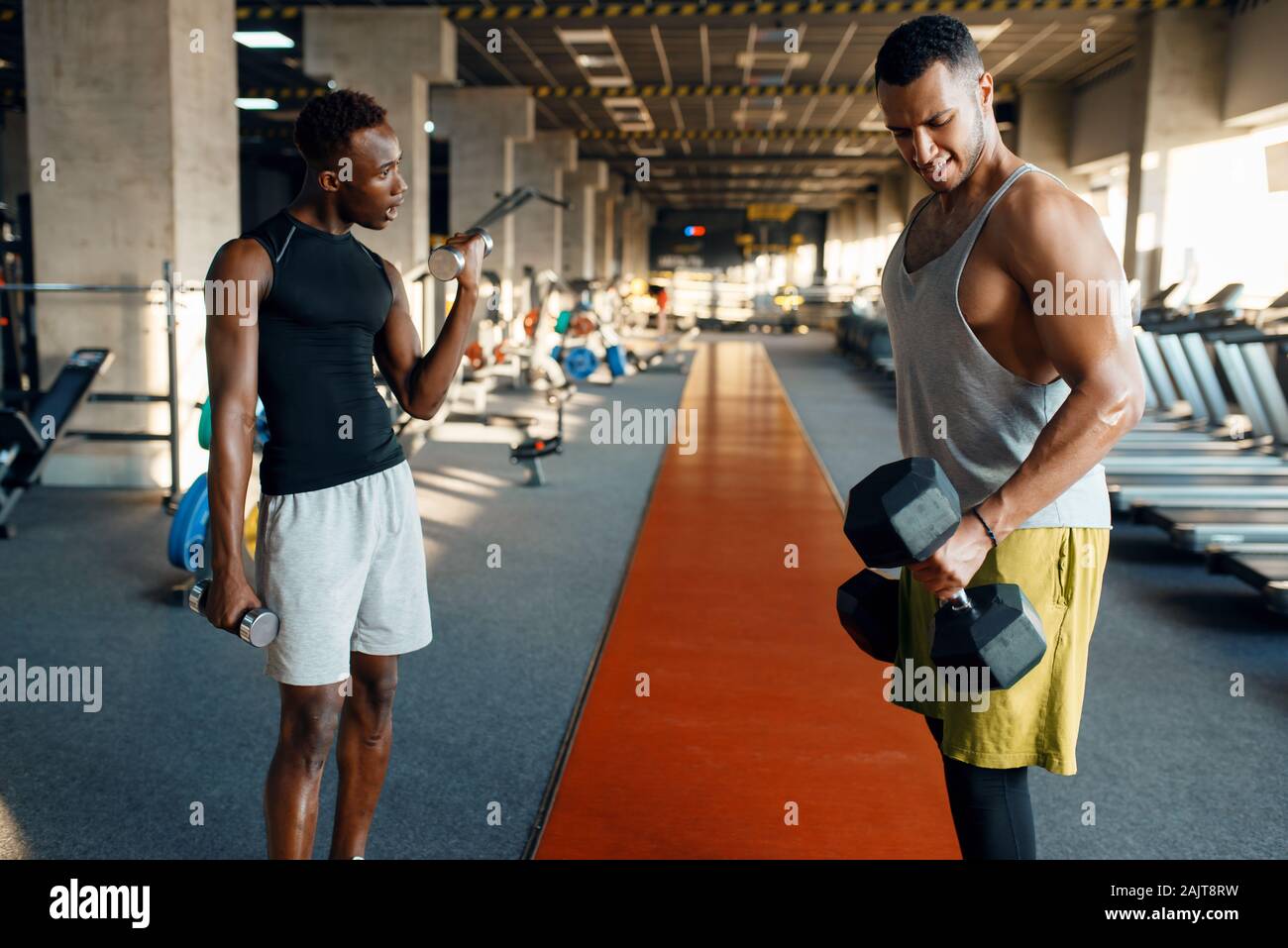 Two tired athletes doing exercise with dumbbells Stock Photo - Alamy