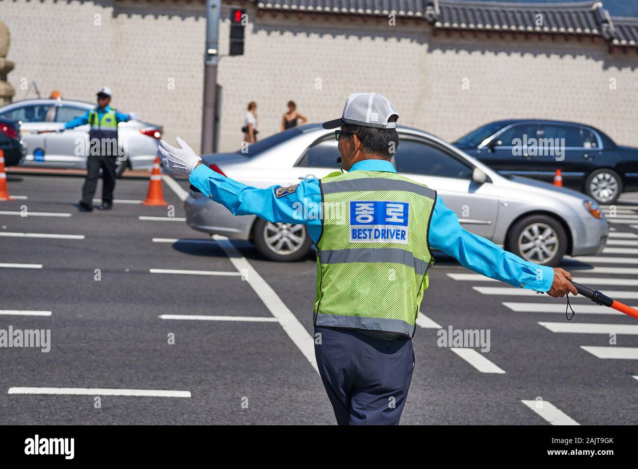 An official in a neon green vest with "best driver" printed on it ...
