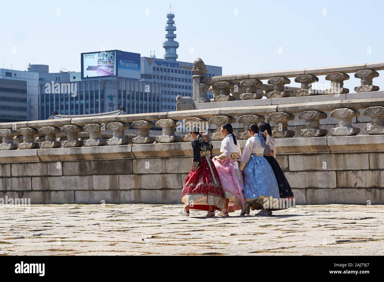 Four female Asian tourists dressed in traditional Korean hanbok walk ...