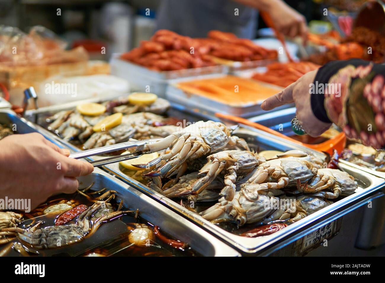 Women's hands point at and grab with tongs ganjang gejang (salted ...