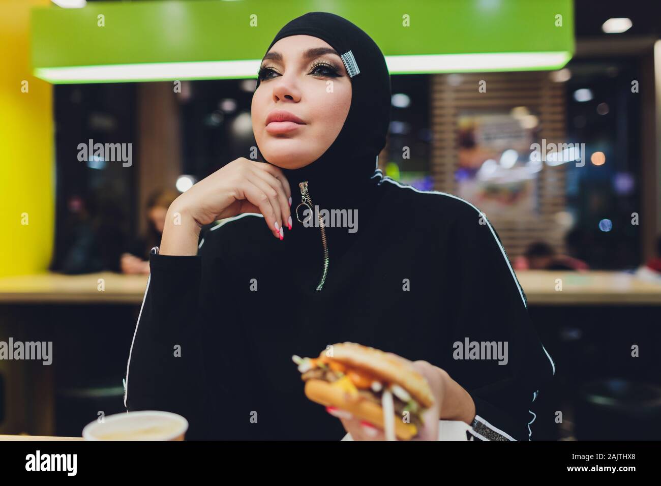 Arab girls at fast food restaurant eating burger Stock Photo - Alamy