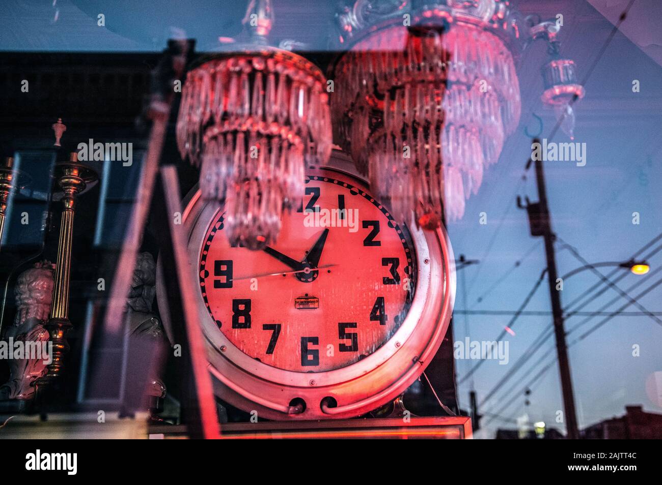 An old antique clock and glass chandelier lit up in pink light in a ...