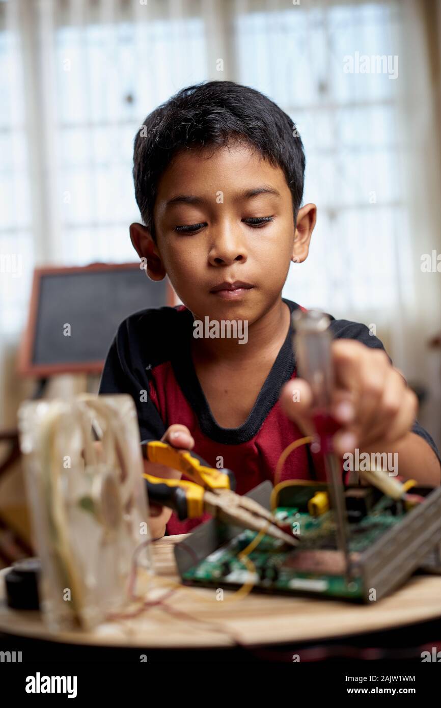 Schoolboy repairing electronic computer part at home Stock Photo - Alamy