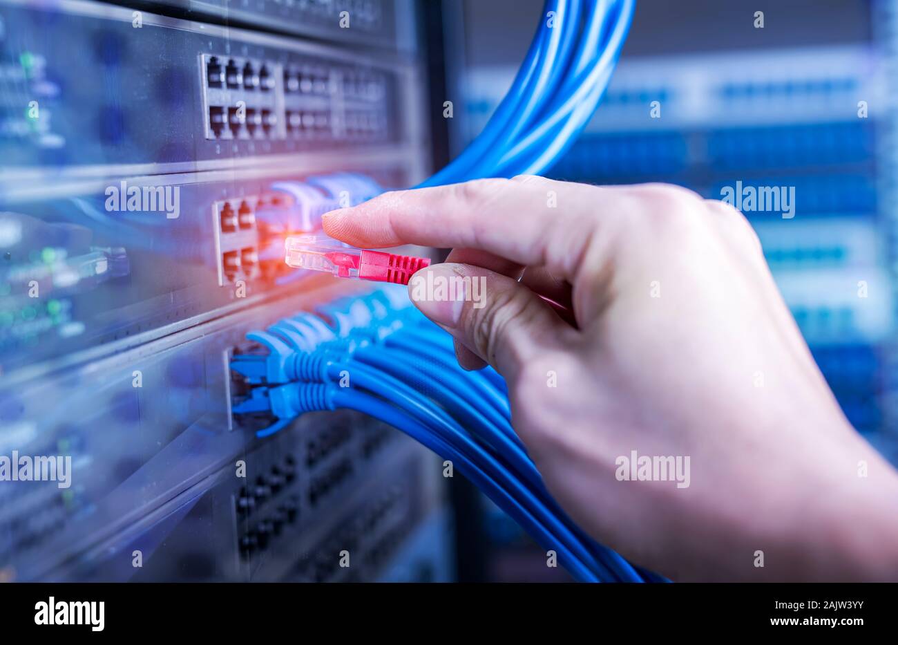 hand plugging red cable in network switch Stock Photo - Alamy