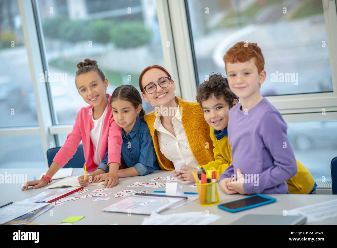 Smiling teacher having fun with children during the lesson Stock Photo ...