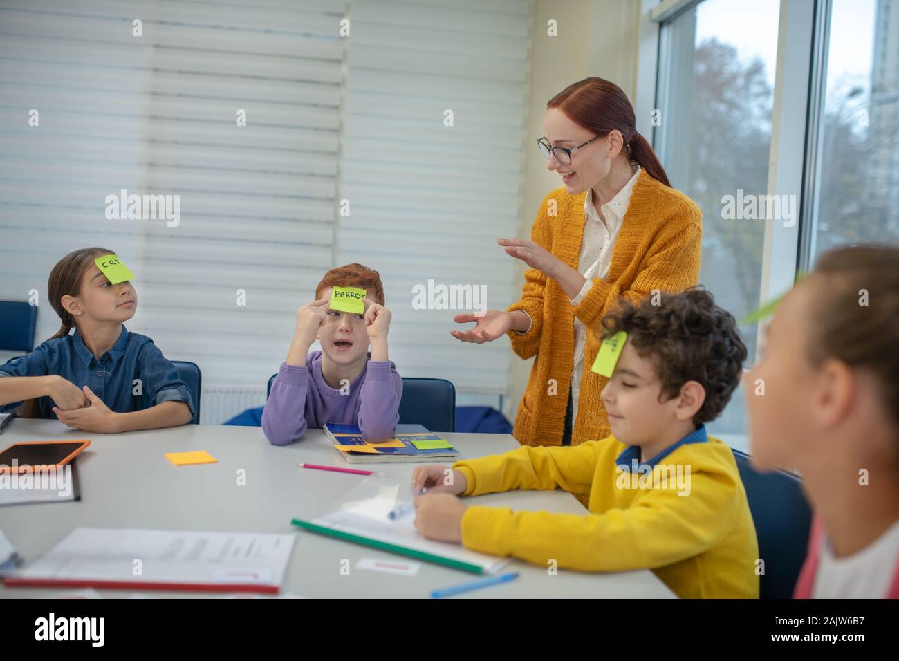 Teacher helping school children playing words game Stock Photo - Alamy