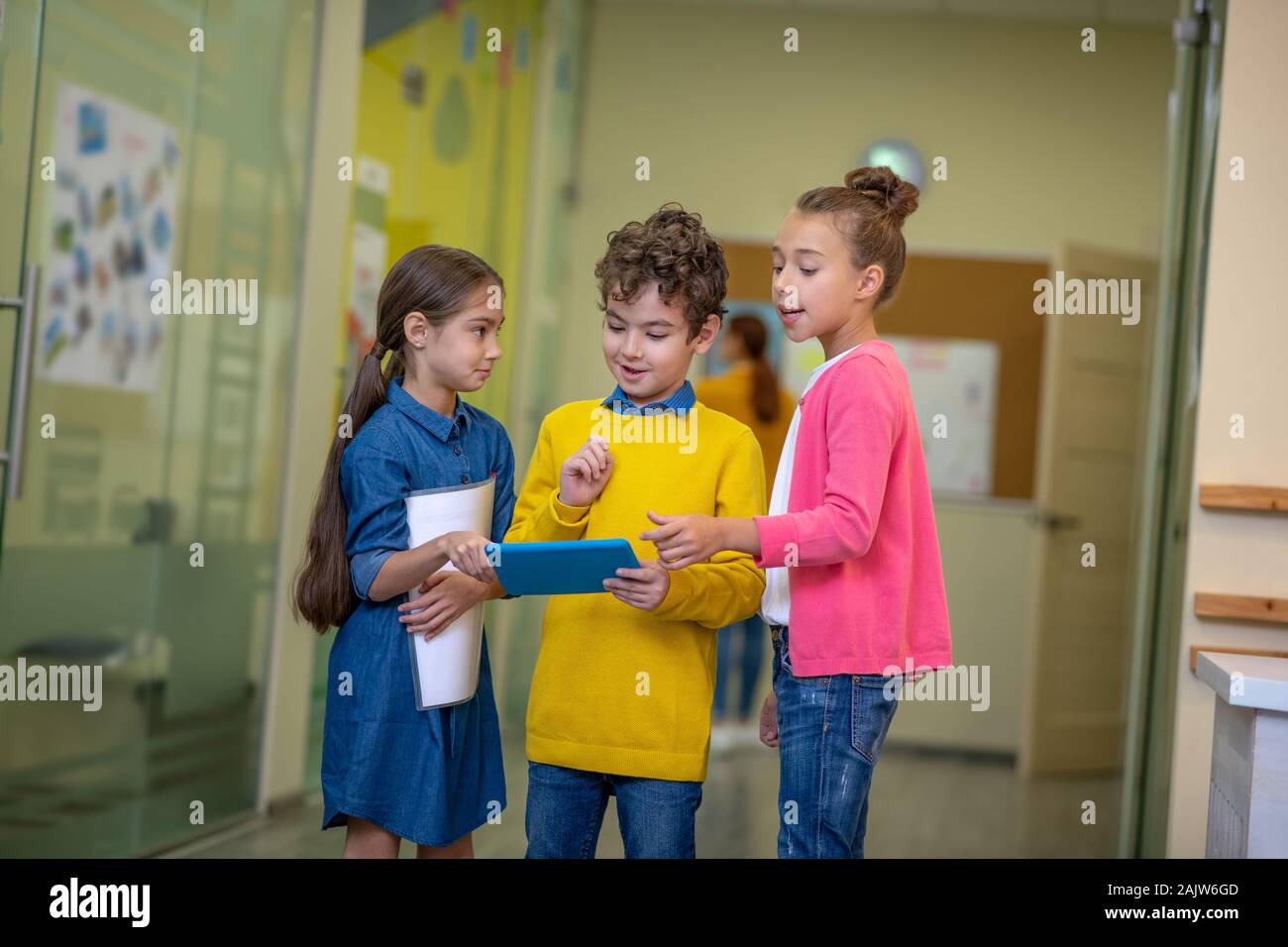 Smiling pupils sharing tablet school corridor hi-res stock photography ...