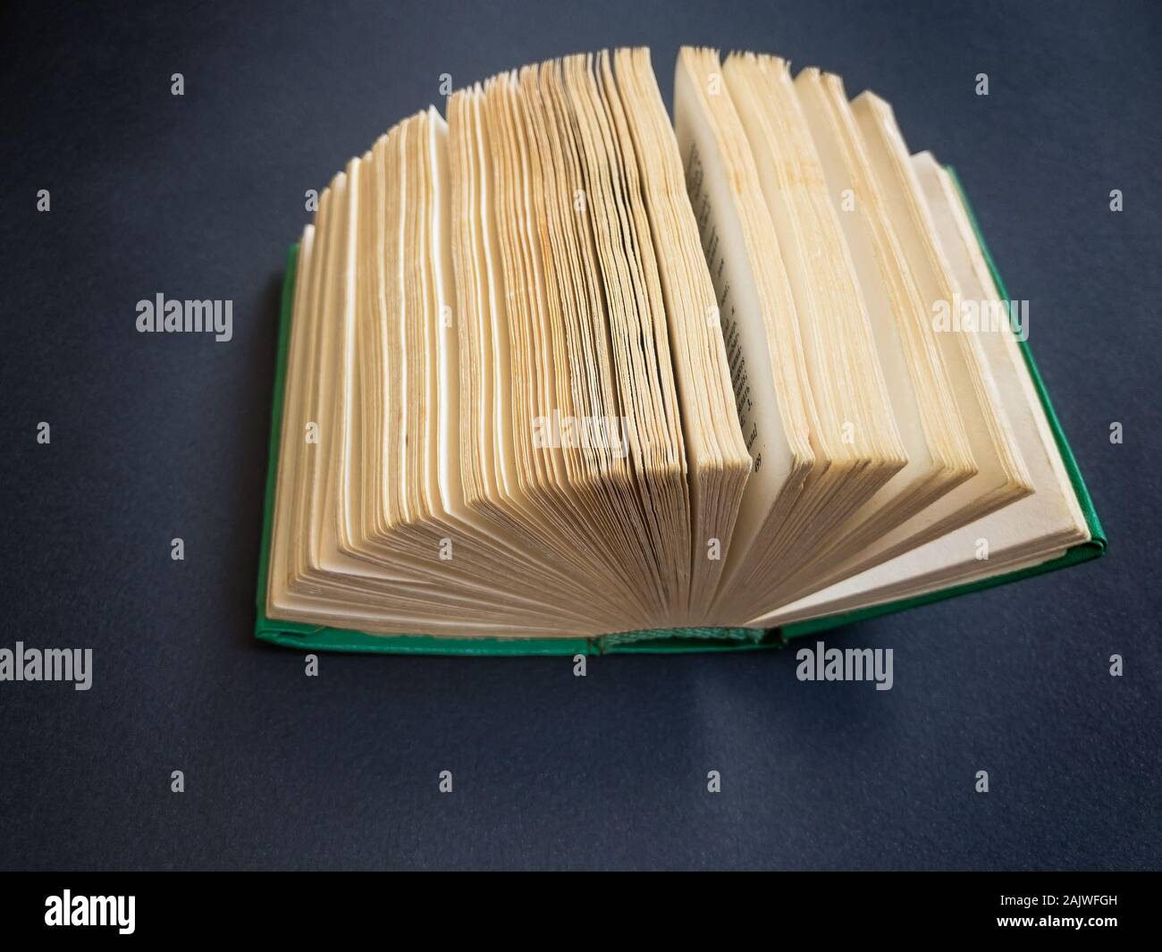 Top view on tiny book lying on a dark paper surface opened like a fan ...