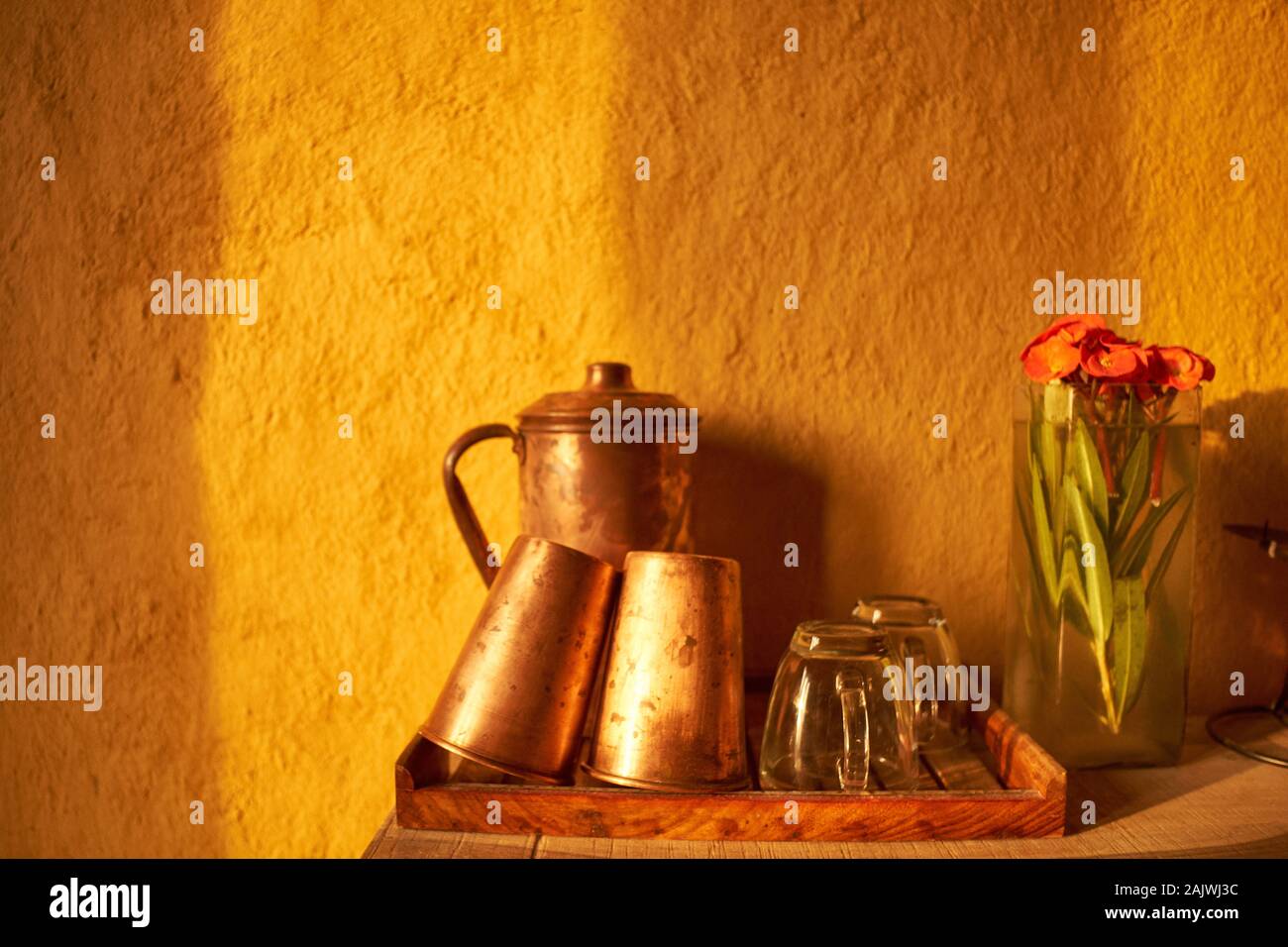 Still life with traditional copper utensils and flowers in a mud walled ...