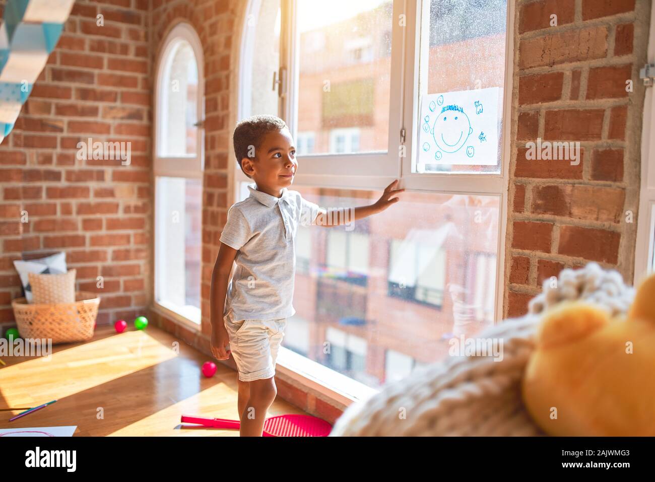 Beautiful african american toddler standing looking through the window ...