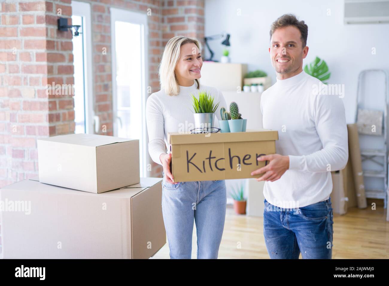 Young beautiful couple moving cardboard boxes at new home Stock Photo ...