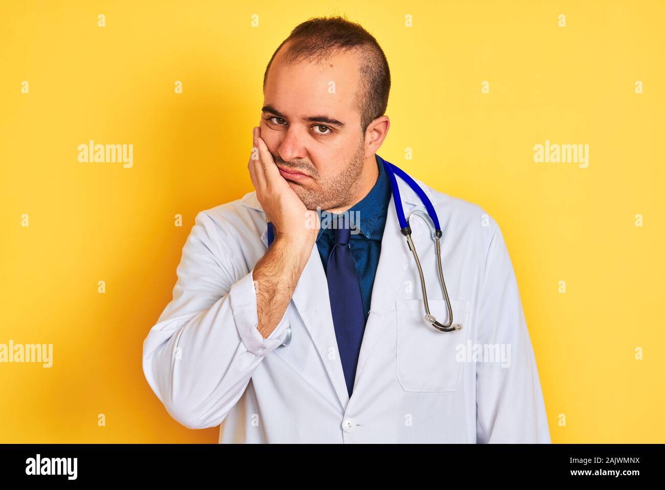 Young doctor man wearing coat and stethoscope standing over isolated ...
