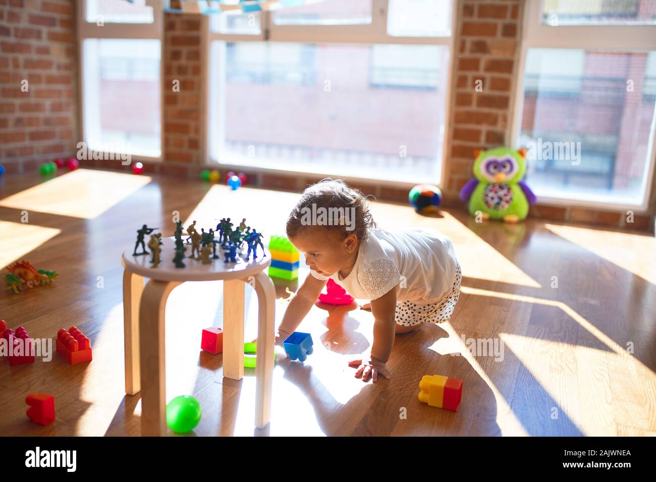 Adorable toddler building pyramid using hoops around lots of toys at ...