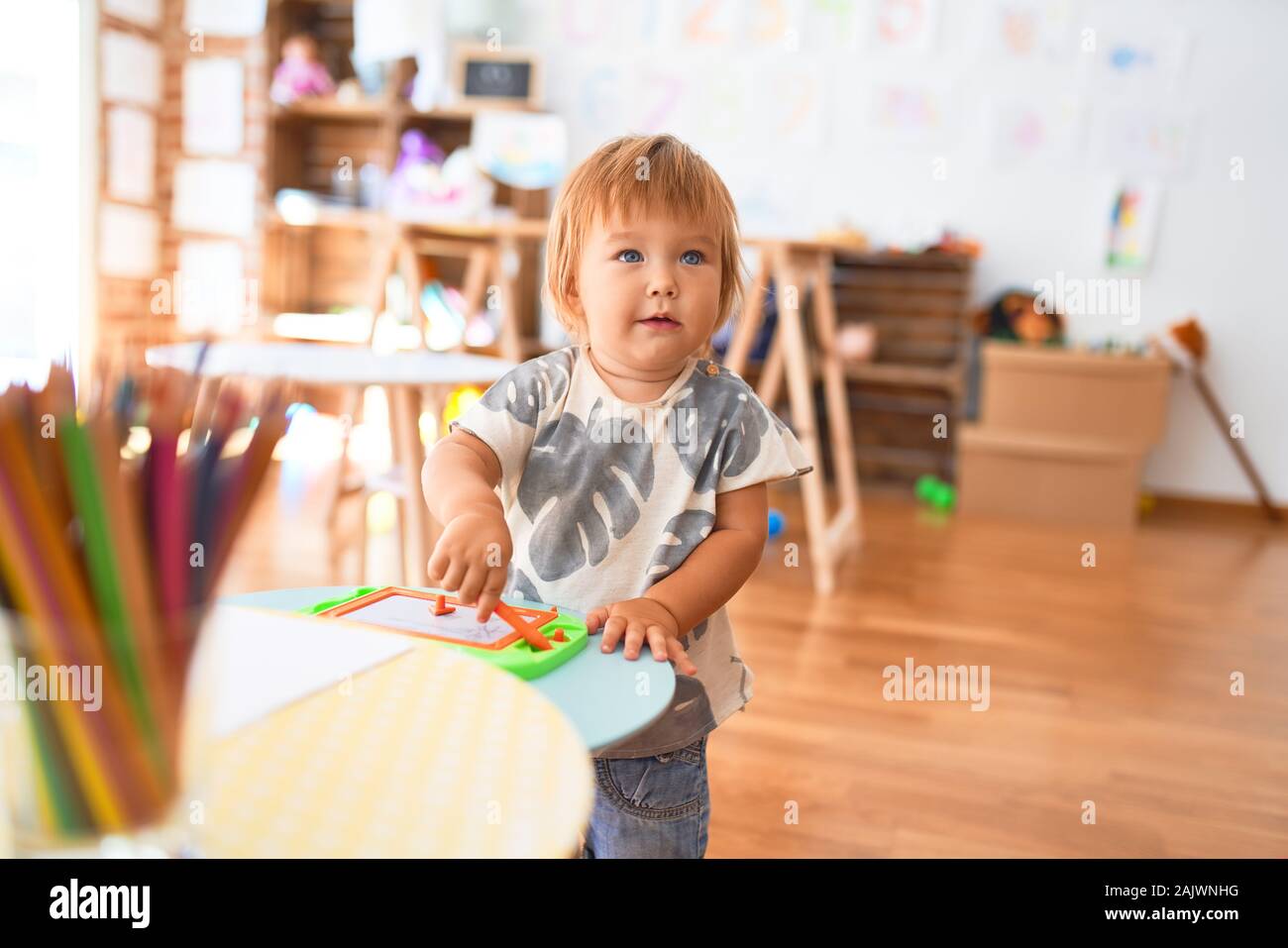 Adorable toddler drawing using digital board around lots of toys at ...