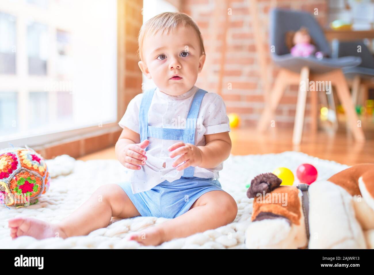 Beautiful toddler sitting on the blanket around lots of toys at ...