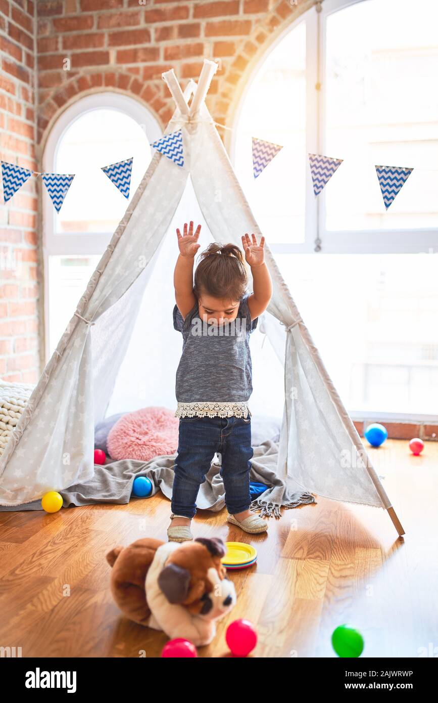 Beautiful toddler standing inside tipi with hands raised smiling at ...