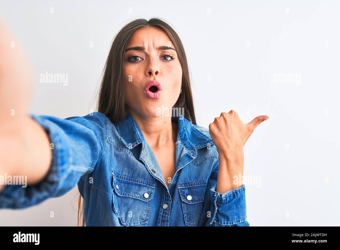 Beautiful woman wearing denim shirt make selfie by camera over isolated ...