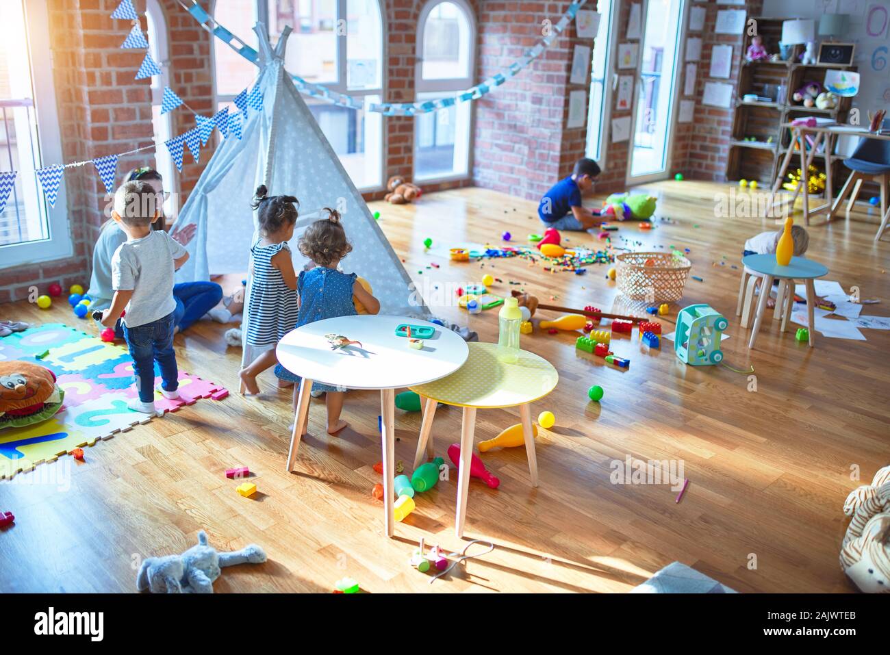 Beautiful teacher and group of toddlers playing around lots of toys at ...
