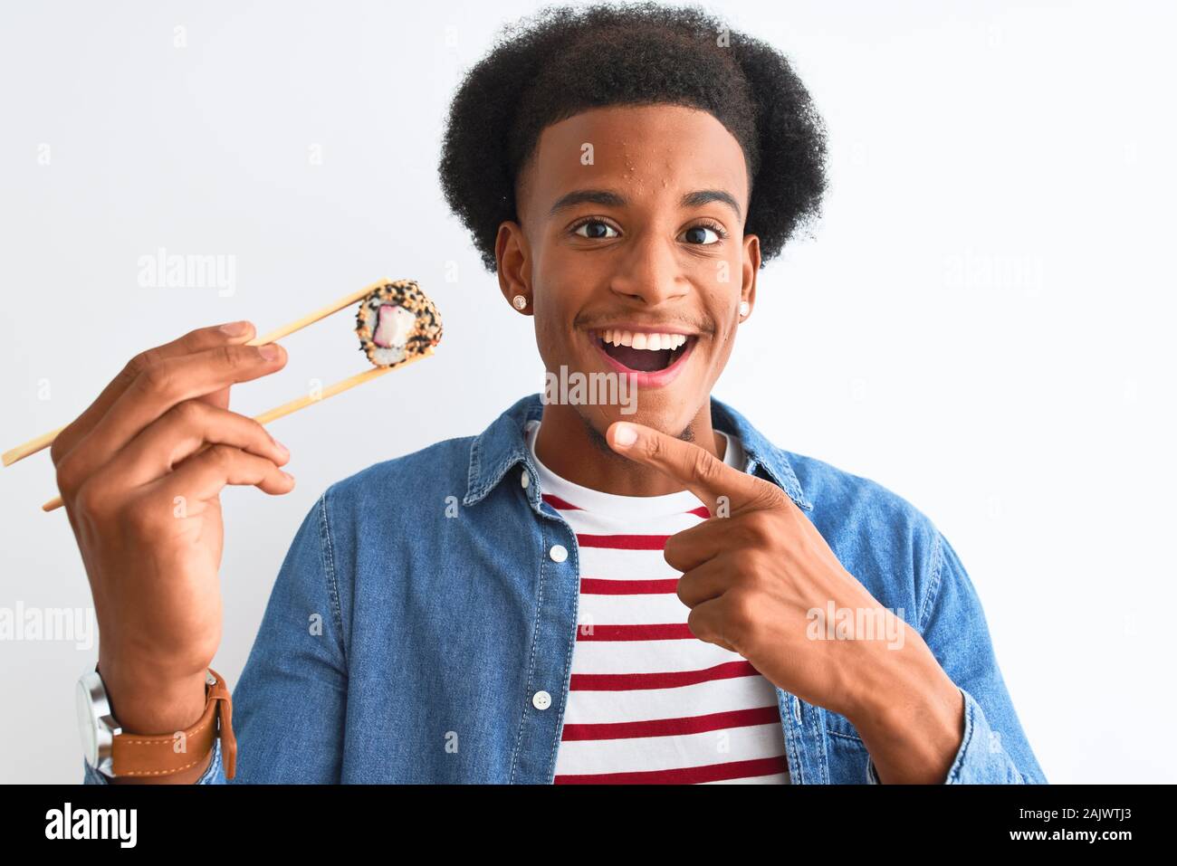 Young african american man eating sushi using chopsticks over isolated ...