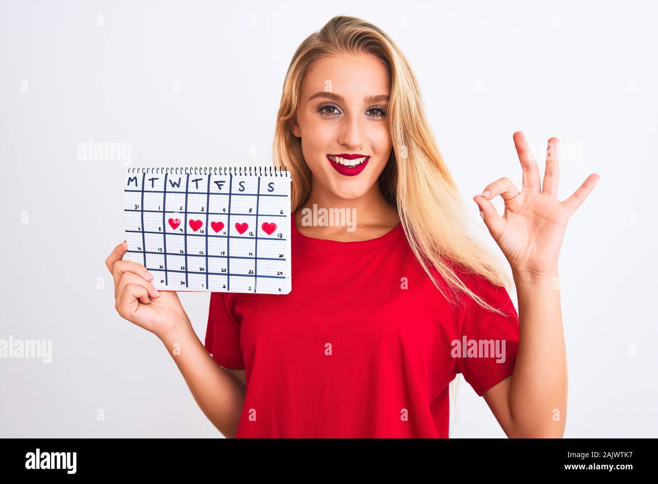 Young beautiful woman holding period calendar standing over isolated ...