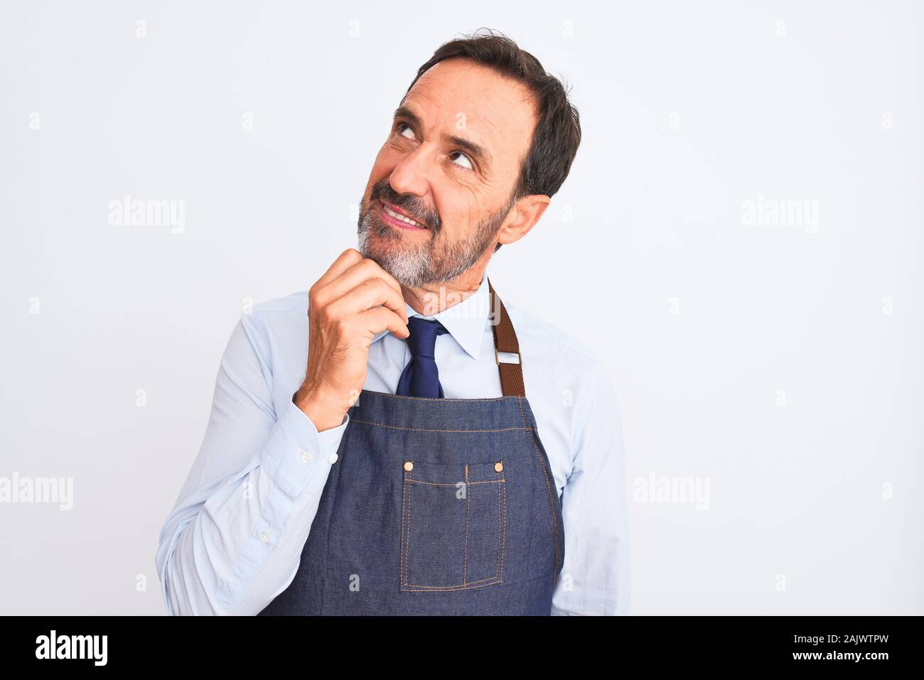 Middle age shopkeeper man wearing apron standing over isolated white ...