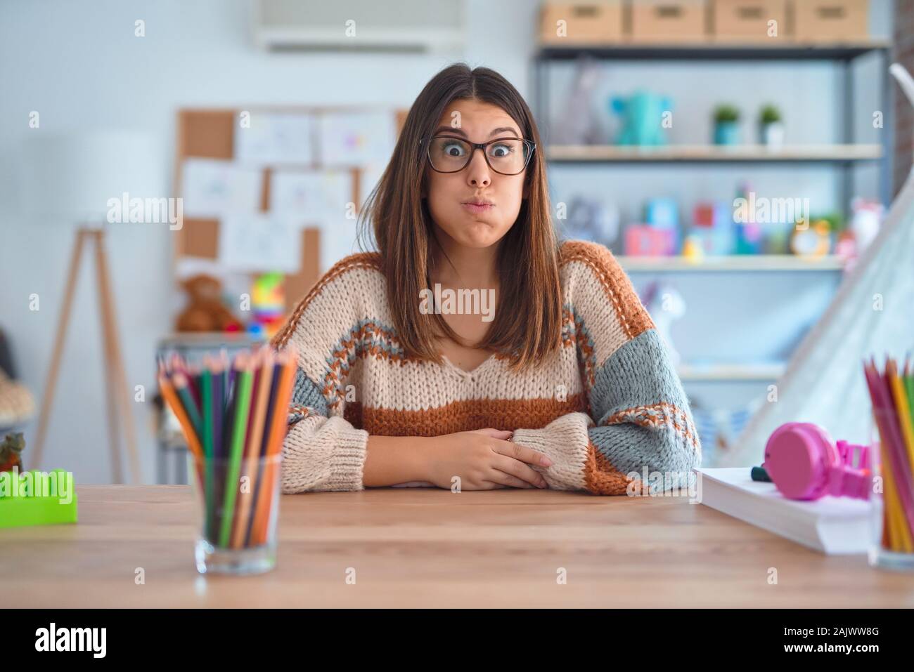 Young beautiful teacher woman wearing sweater and glasses sitting on ...