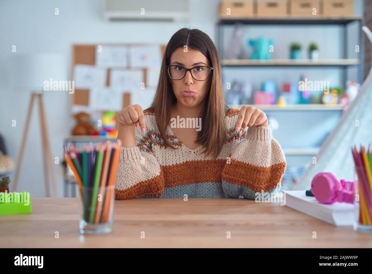 Young beautiful teacher woman wearing sweater and glasses sitting on ...