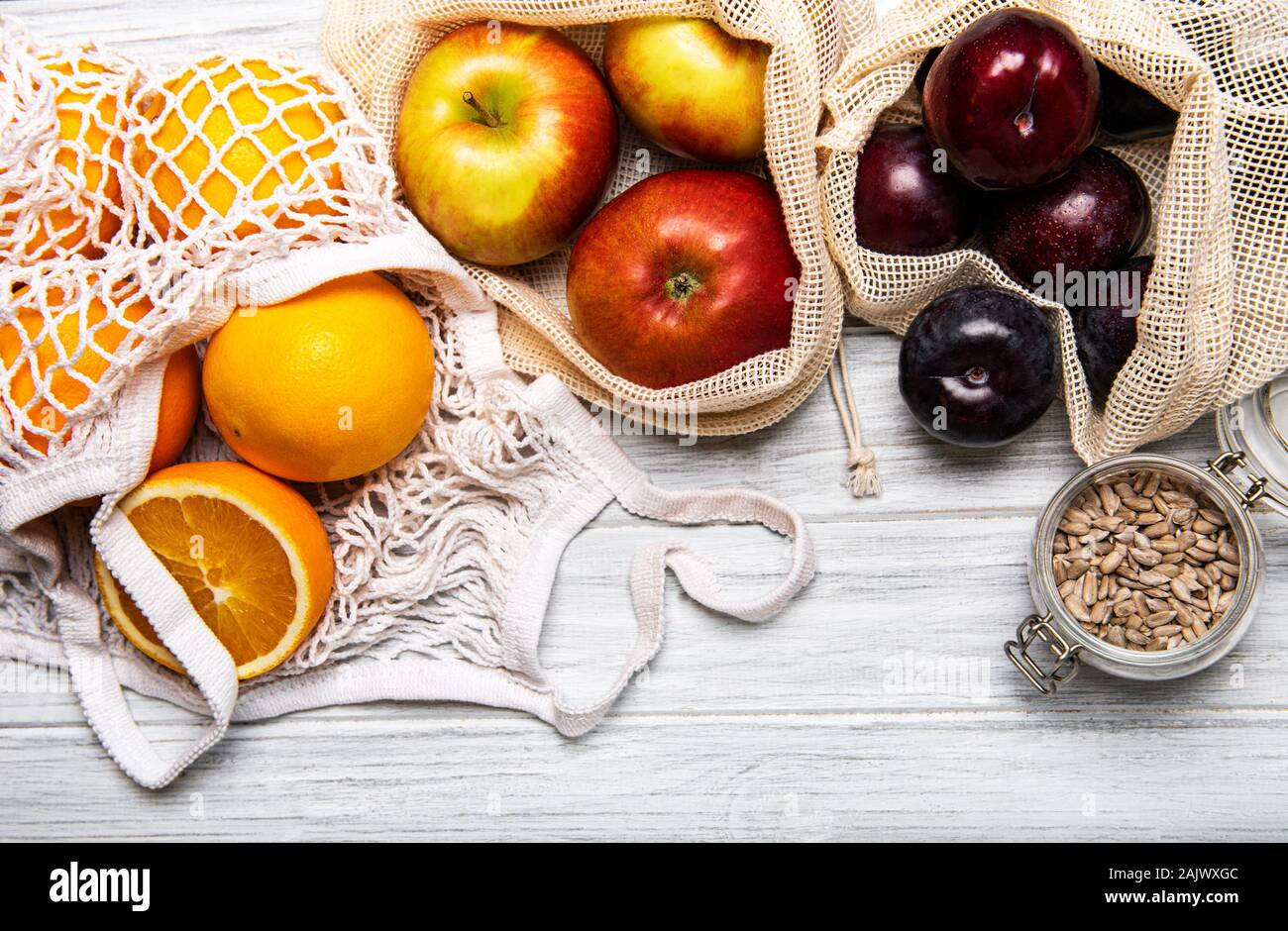Mesh shopping bags with organic fruits on wooden background. Flat lay ...