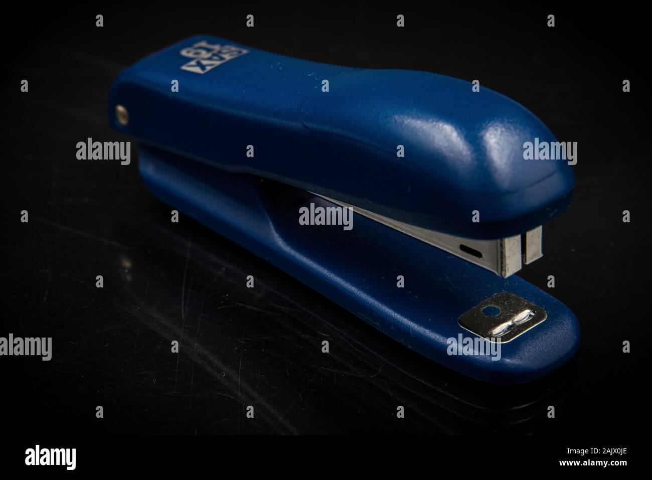 Office stapler blue against black background Stock Photo - Alamy