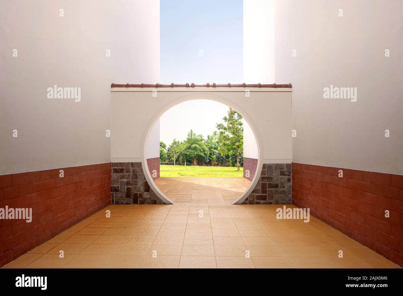 Chinese round gate with view of green grass and trees over blue sky ...