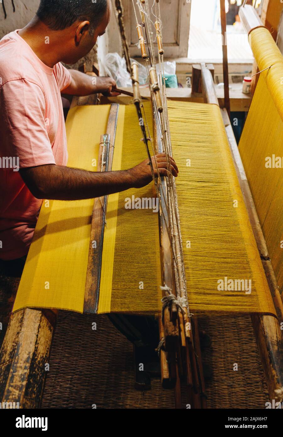 Hand weaving a yellow kashmiri pashmina shawl with light source coming ...